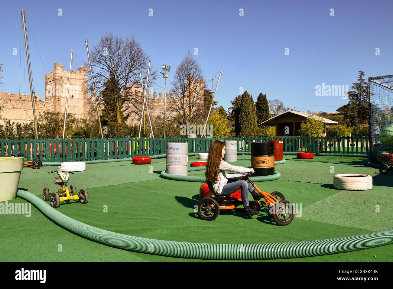 Long-haired little girl (9 years old) riding on a pedal car in a ...