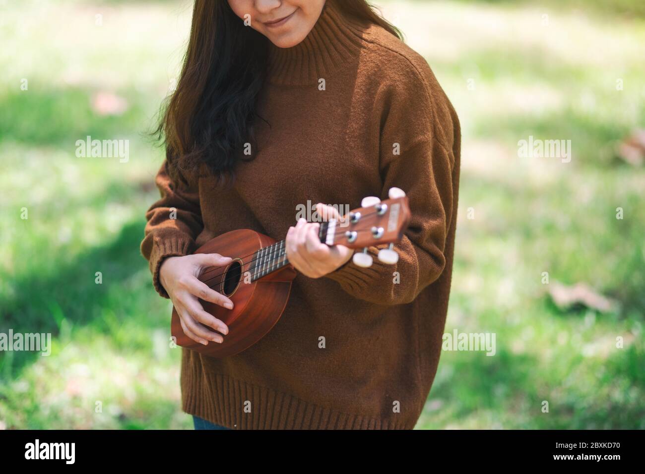 A woman standing and playing ukulele in the outdoors Stock Photo - Alamy