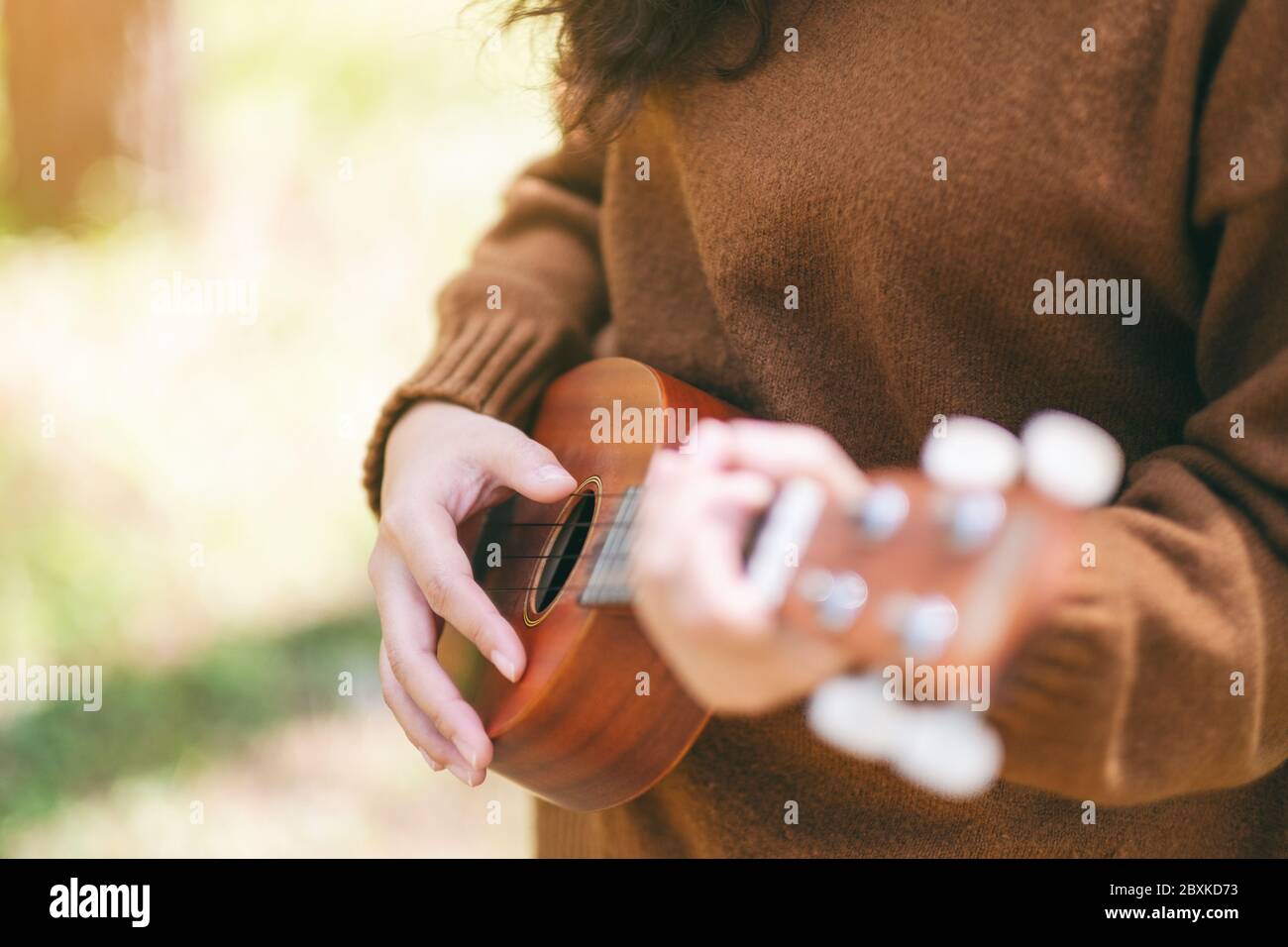 A woman standing and playing ukulele in the outdoors Stock Photo - Alamy