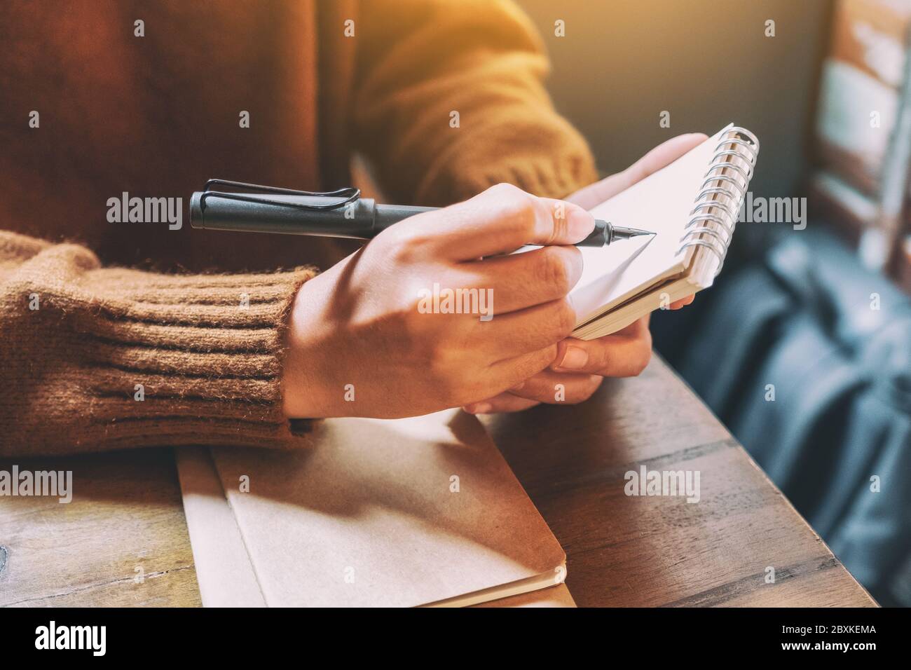 Closeup image of a woman holding and writing on blank notebook with ...