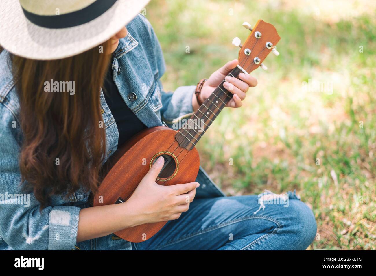 A woman sitting and playing ukulele in the outdoors Stock Photo - Alamy