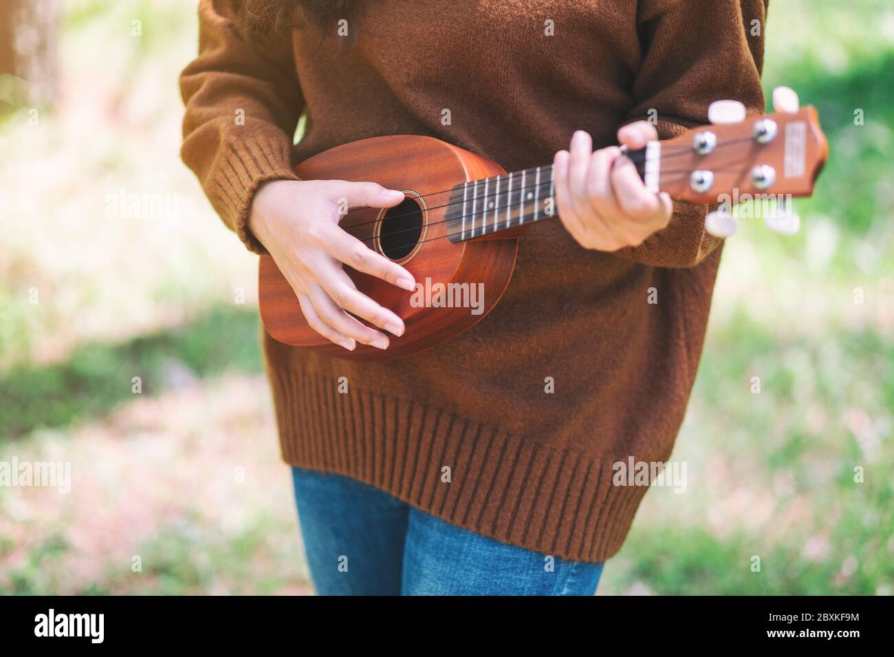 A woman standing and playing ukulele in the outdoors Stock Photo - Alamy