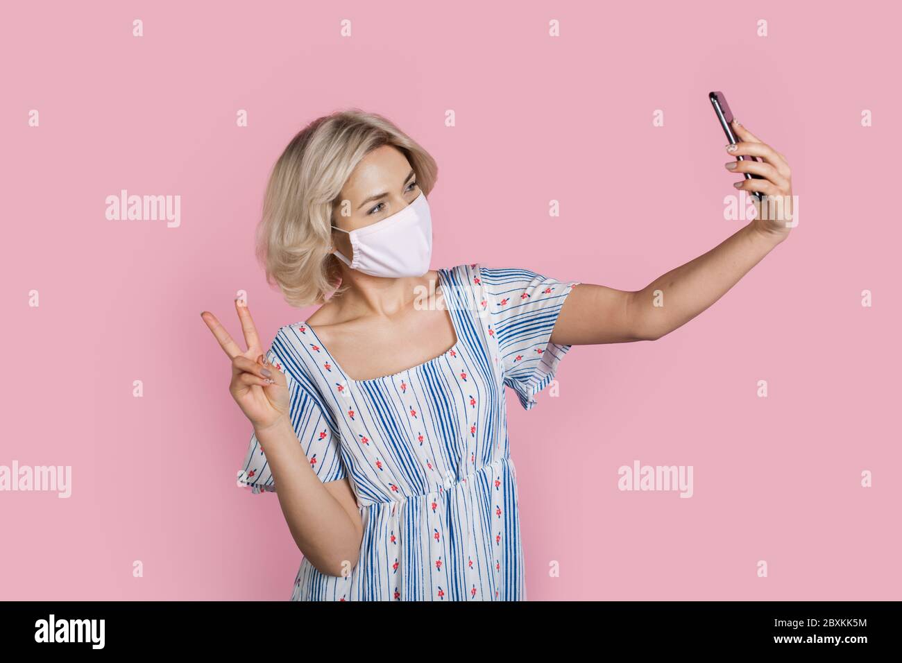 Blonde caucasian woman making a selfie gesturing the peace sign wearing ...