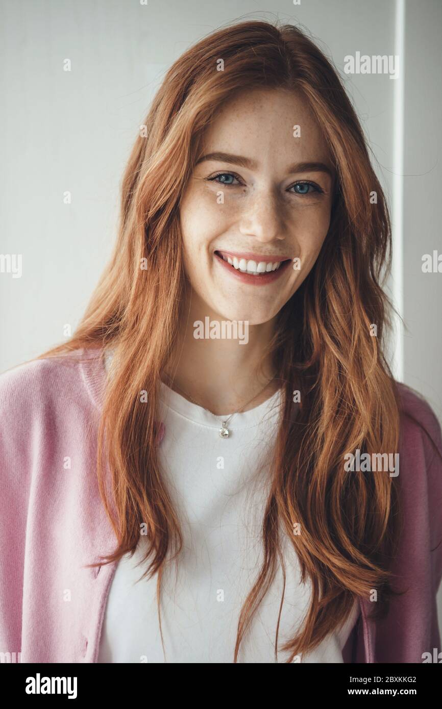 Ginger lady with freckles smiling toothily at camera wearing a white ...