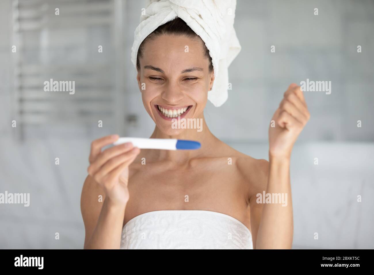 Head shot happy young woman looking at pregnancy test Stock Photo - Alamy