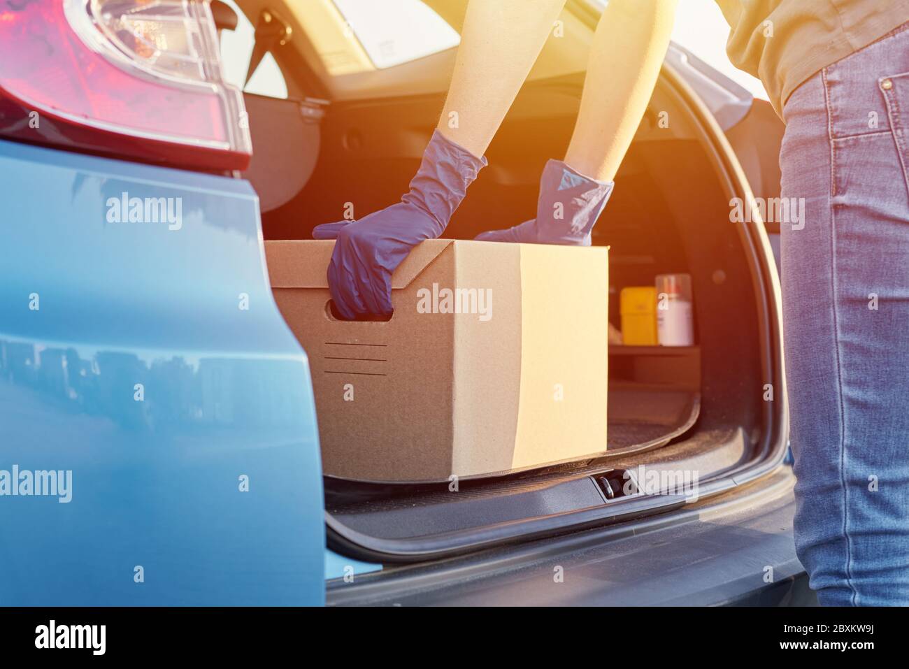 Delivery and volunteering concept. Woman in gloves load box in car ...