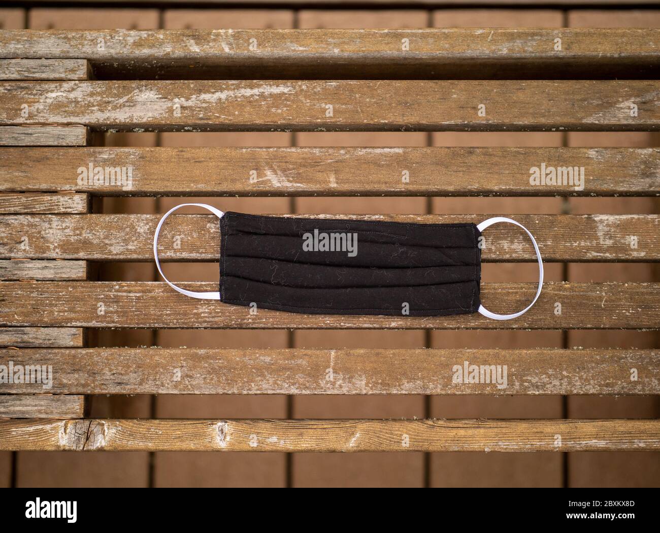 DIY handmade cotton face mask sitting on a wooden bench. Homemade COVID ...