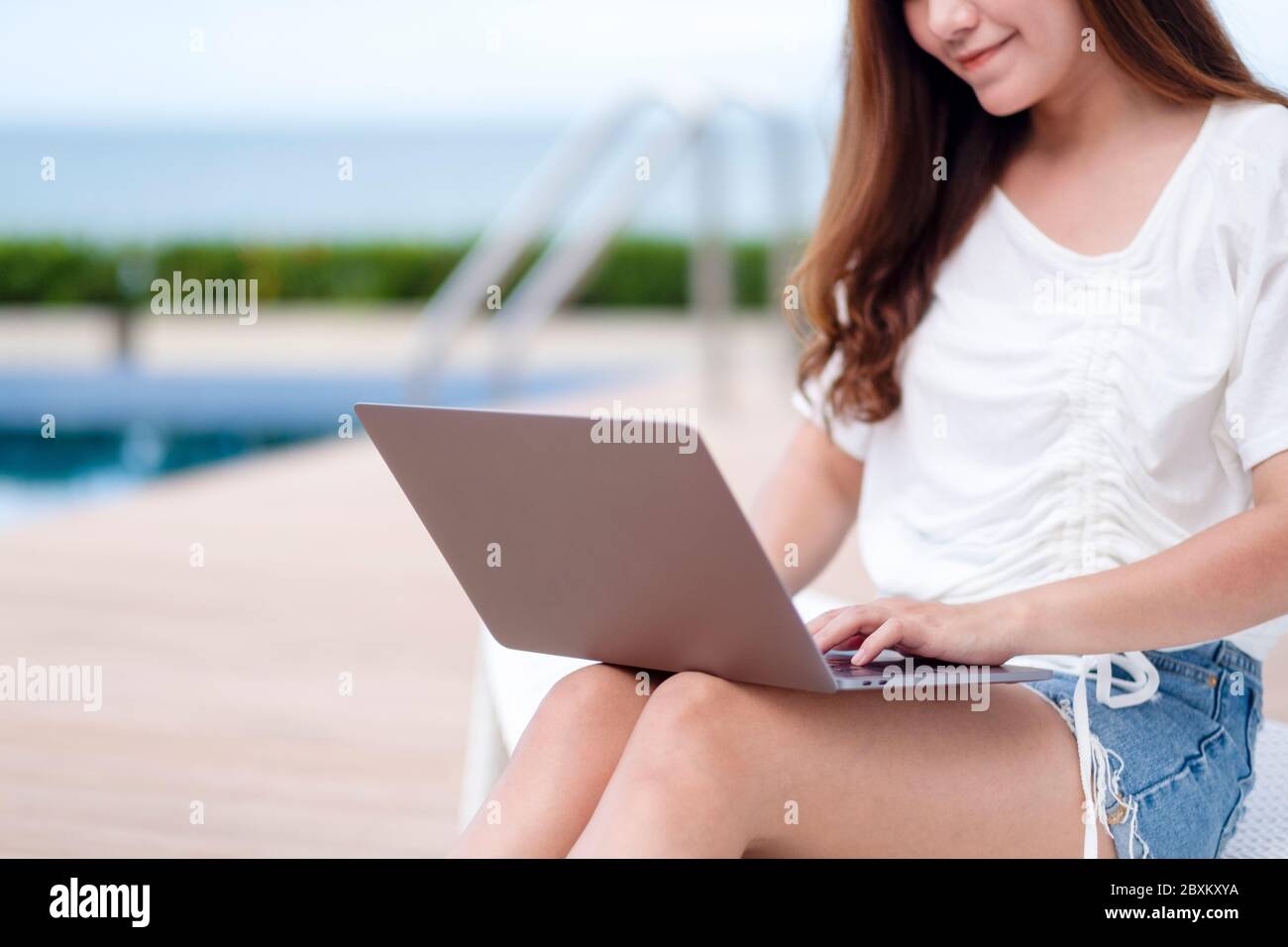 Woman using laptop swimming pool hi-res stock photography and images ...