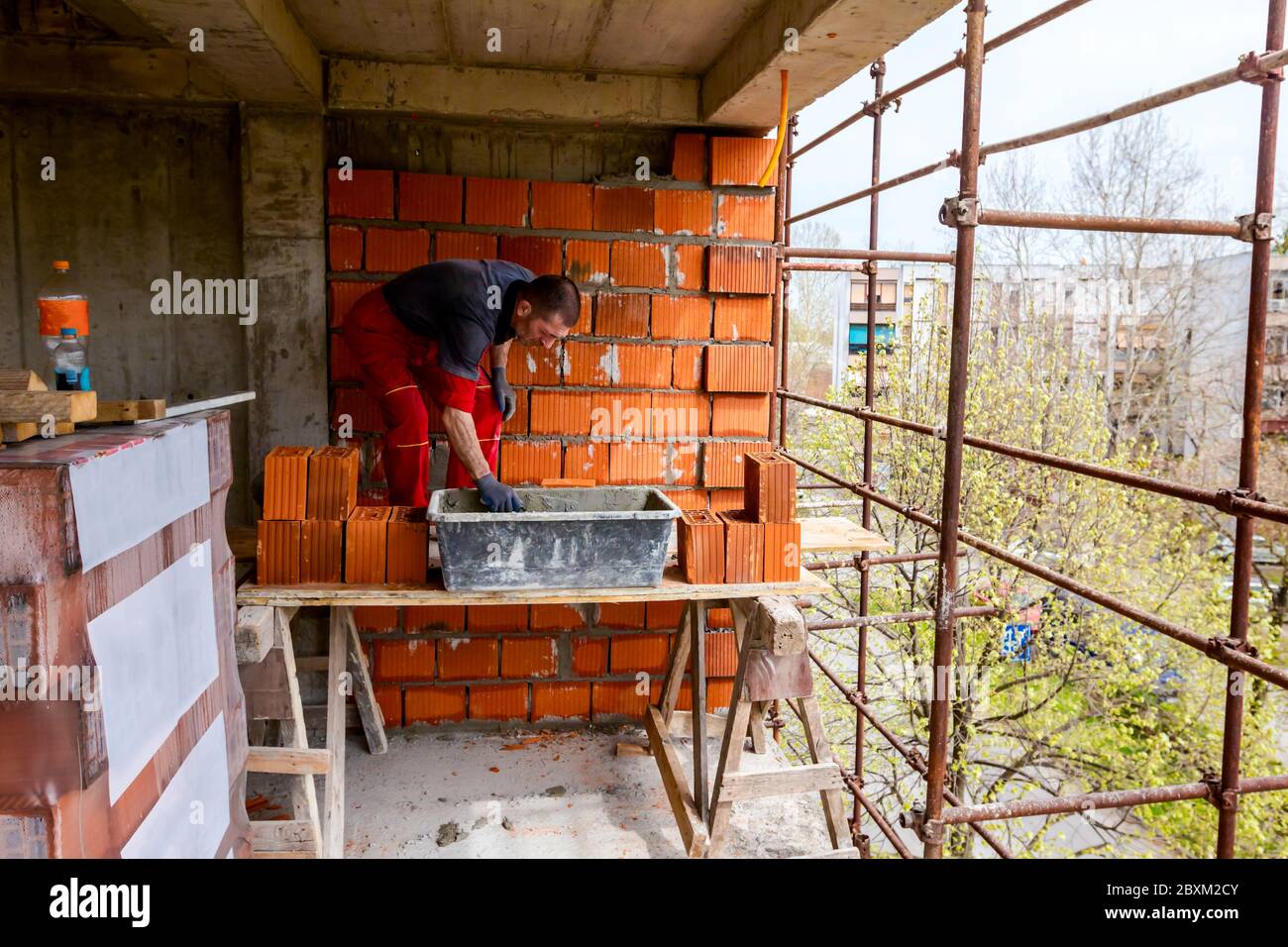 Mason, bricklayer worker is using red blocks to mount a wall at ...