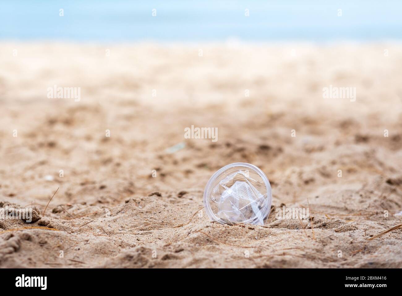 Closeup image of a plastic glass garbage on the beach Stock Photo - Alamy