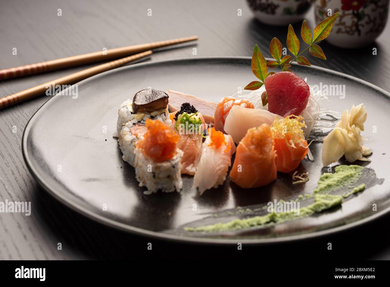 sushi sashimi niguiri wasabi on dark ceramic plate chopsticks and cups ...