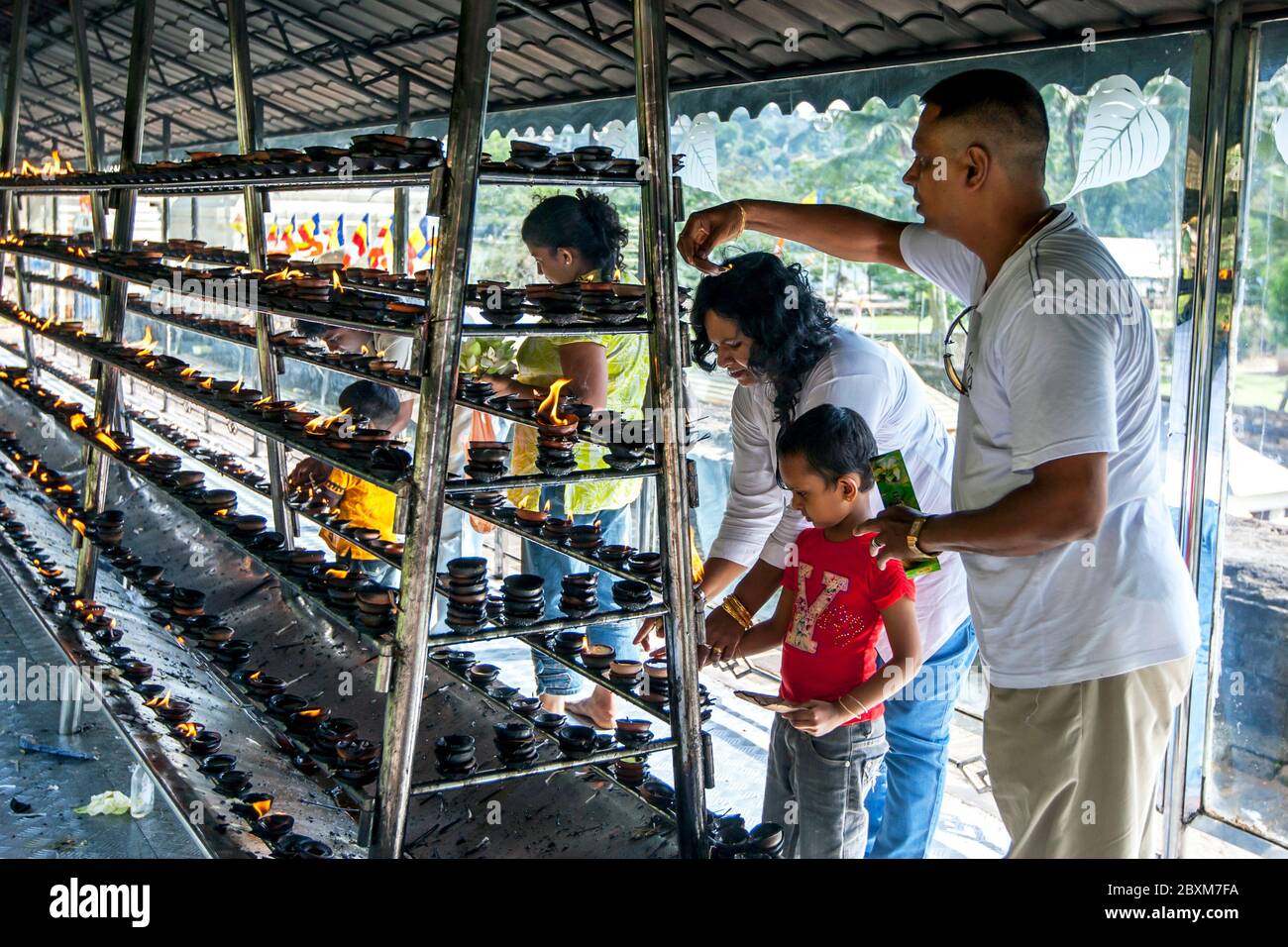 Worshipers lighting oil lamps at the Temple of the Sacred Tooth Relic ...