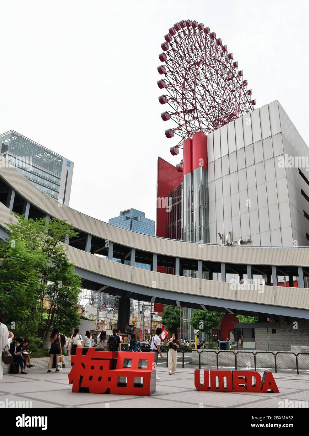 Pedestrians wearing face masks walk near the shopping mall HEP Five at Umeda, Osaka, Japan on ...
