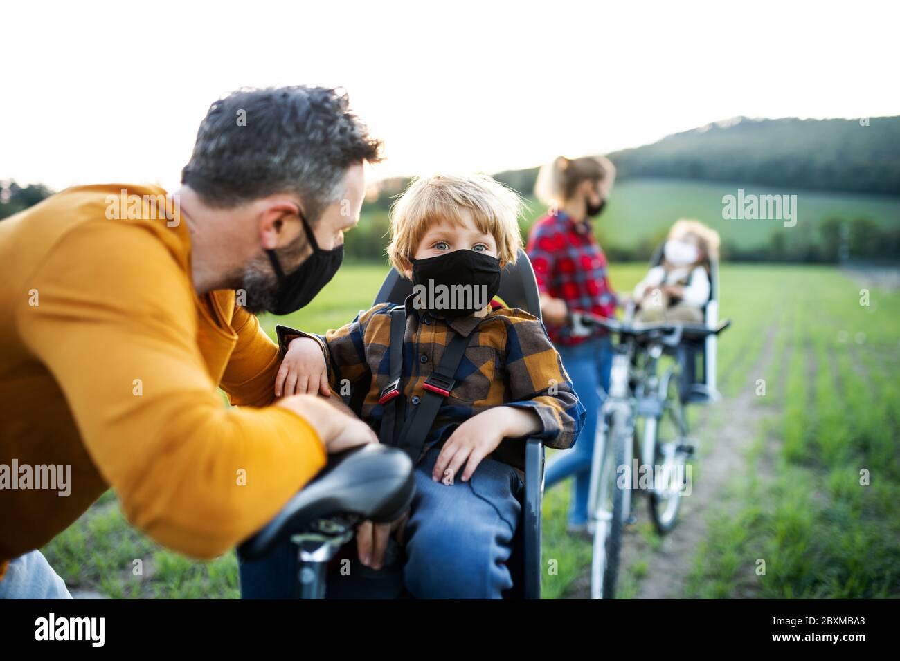 Family with two small children on cycling trip, wearing face masks ...