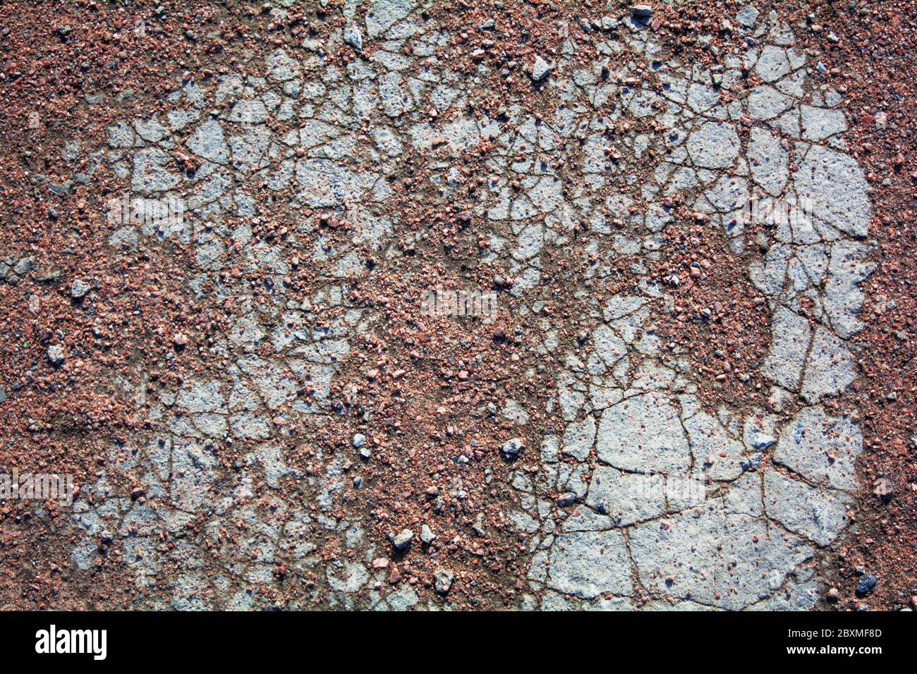 Damaged asphalt pavement road with cracks and red gravel. Ruined urban ...