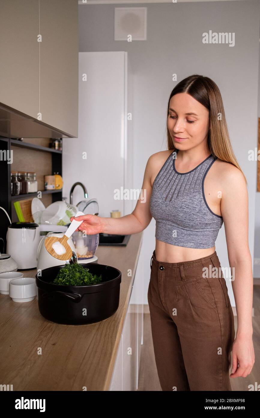 Young fit woman cooking healthy food in a modern kitchen using ...