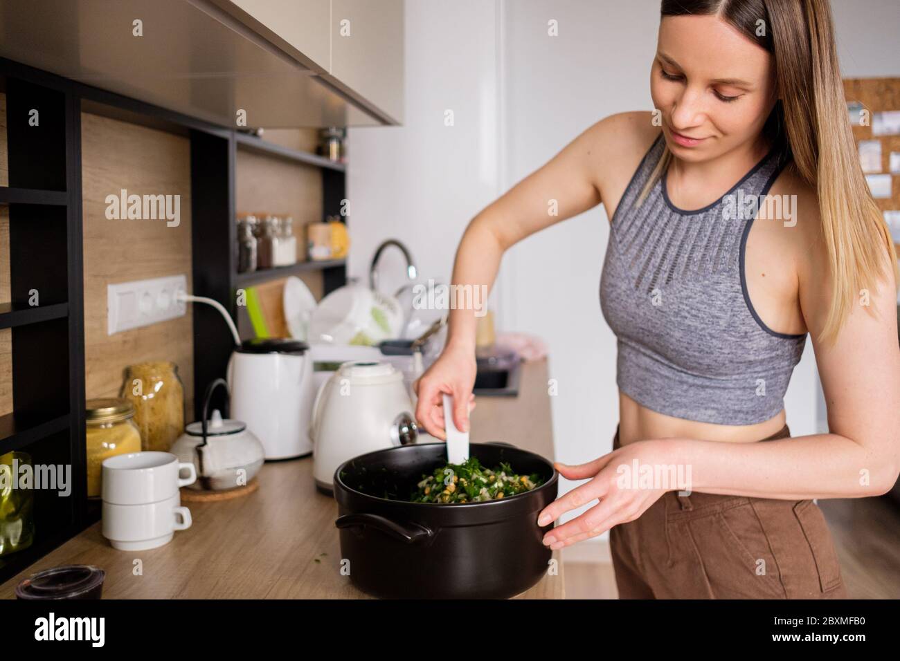 Young fit woman cooking healthy food in a modern kitchen using ...