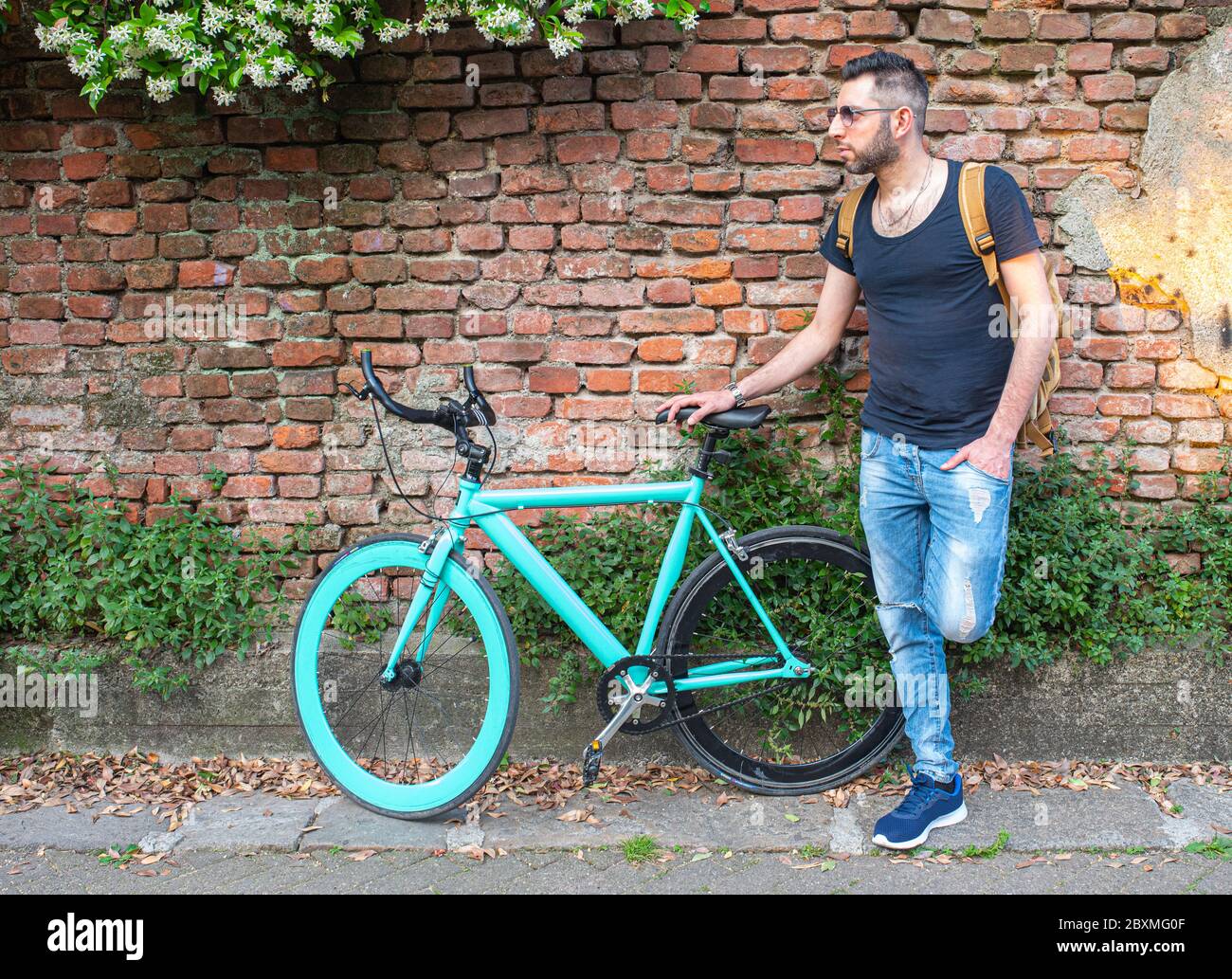 fashionable man portrayed next to his beautiful minimal bicycle ...