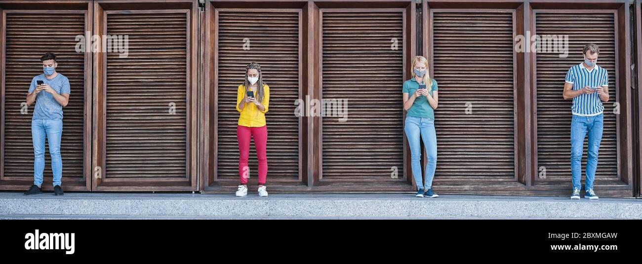 Young people wearing face safety masks using smart mobile phones while ...