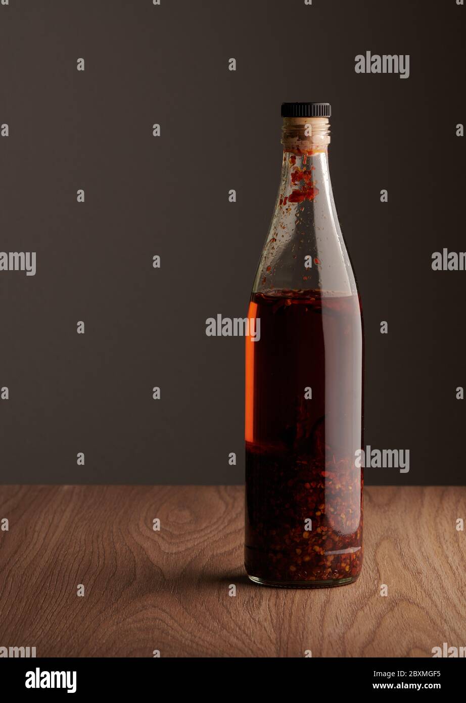 Transparent bottle of homemade chilli oil with pieces of dry chilli, on ...