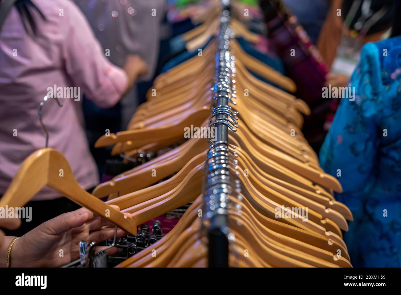 close up to hangers on the bar in cloth shop with a lot of people ...