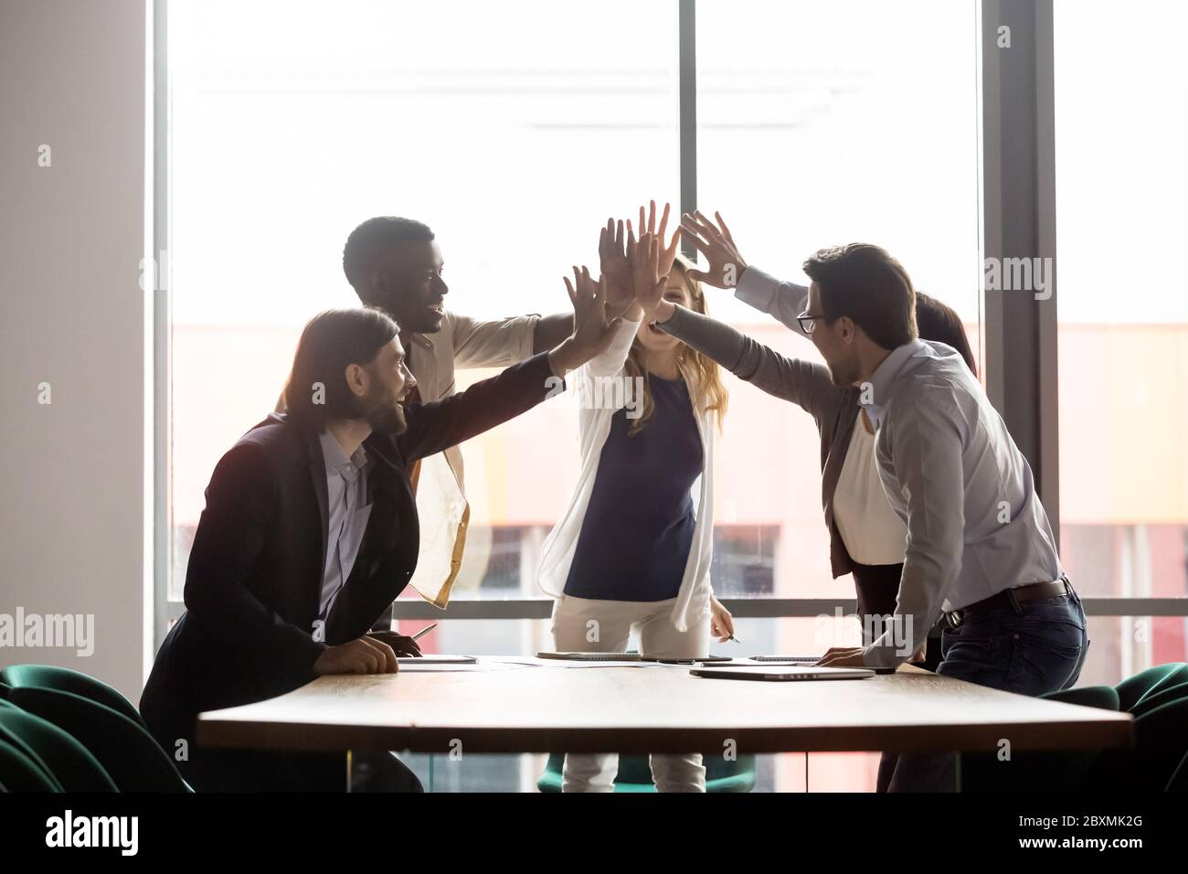 Multiethnic business people giving high five celebrating common success ...