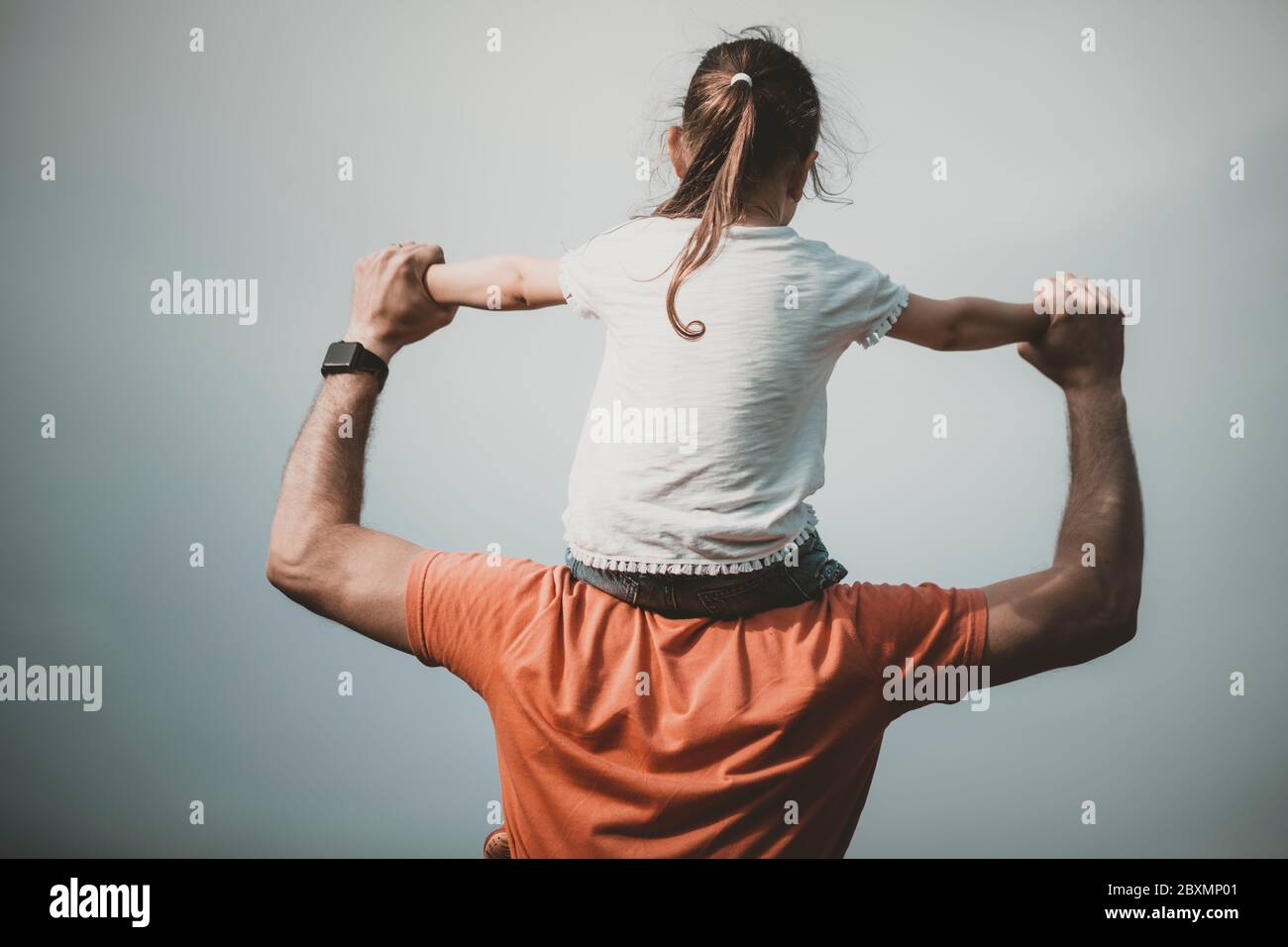 Back view image of father holding daughter on his shoulders. Father and ...