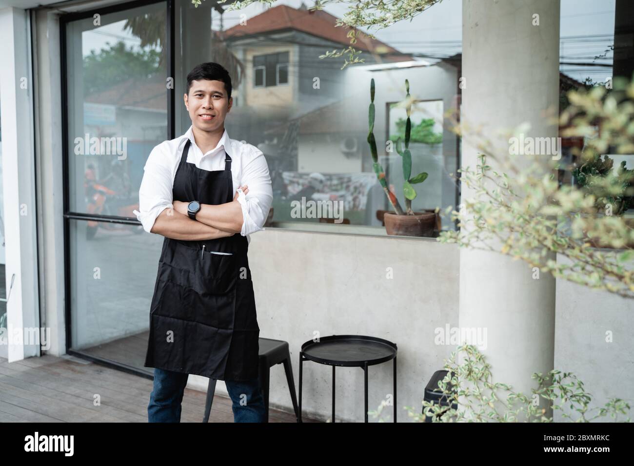 cafe male waitress standing with crossed hands pose in preparation for ...