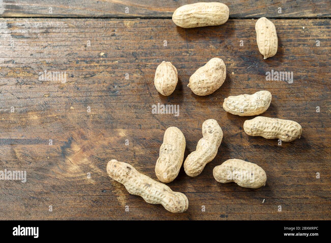 Inshell peanuts sprinkled on a brown wooden background. traditional ...
