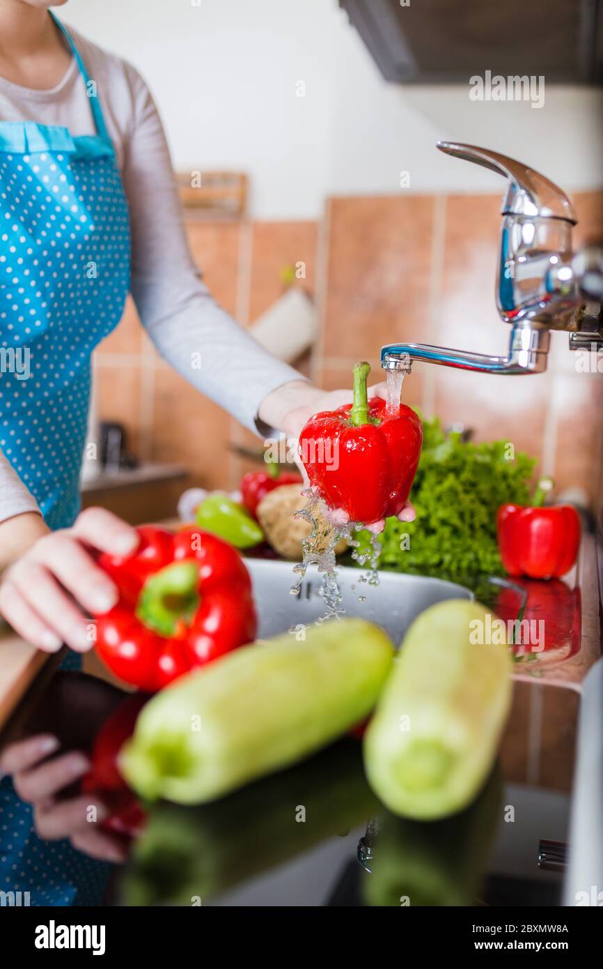 Housewife washing paprika in kitchen sink. Homemade food preparation ...