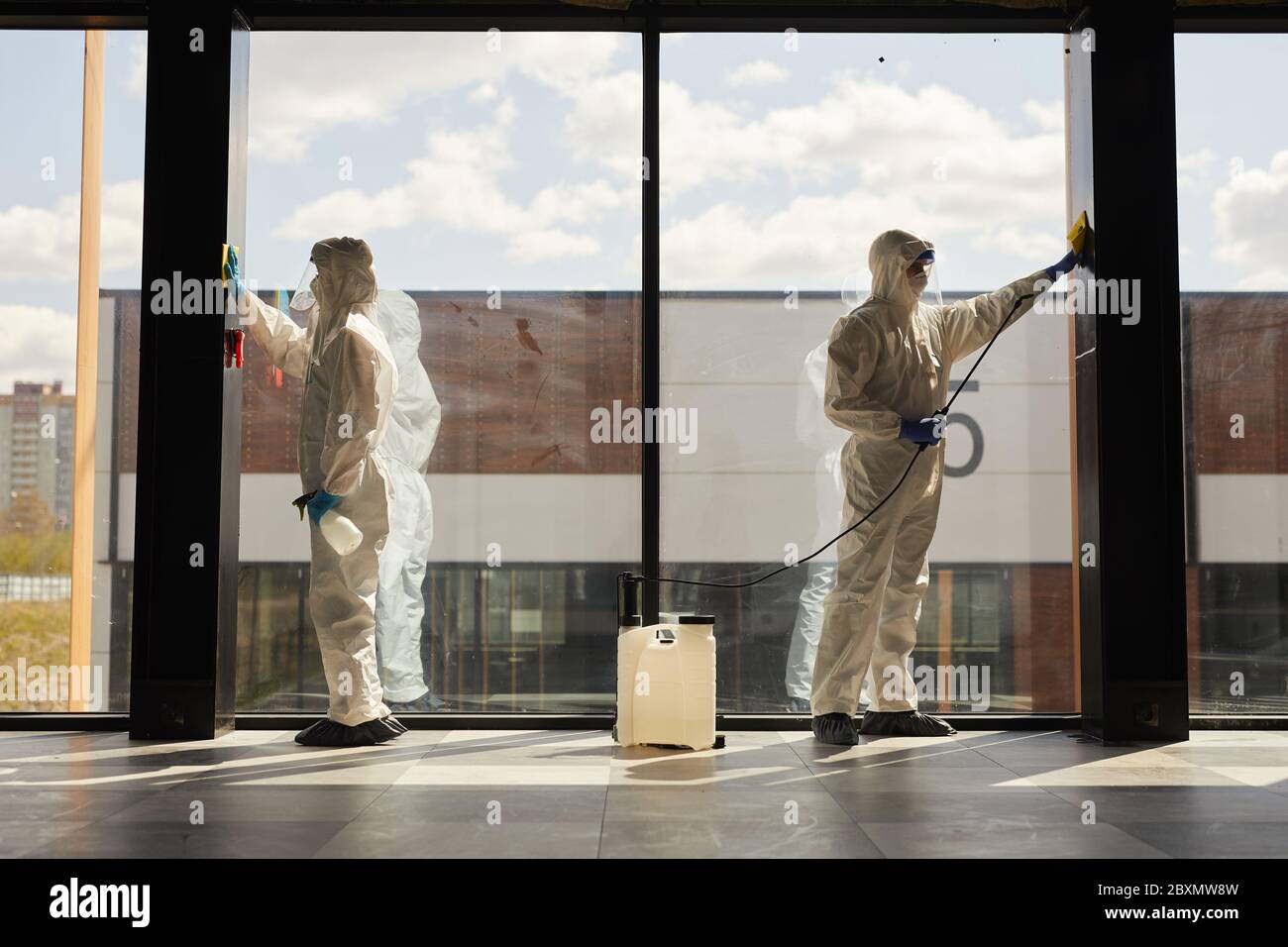 Graphic full length portrait of two workers wearing protective suits ...