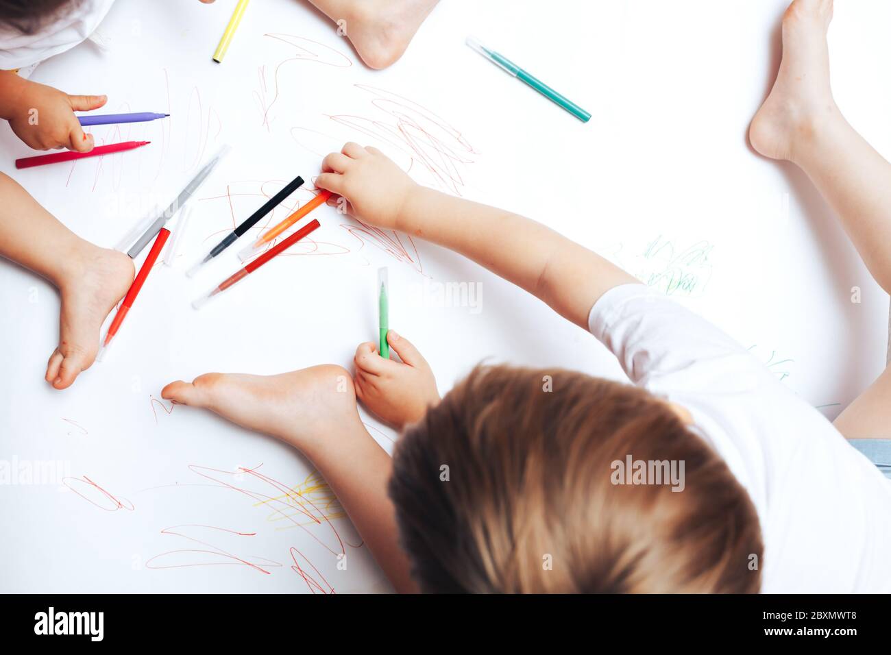 Talented children draw with colored felt-tip pens on white paper ...