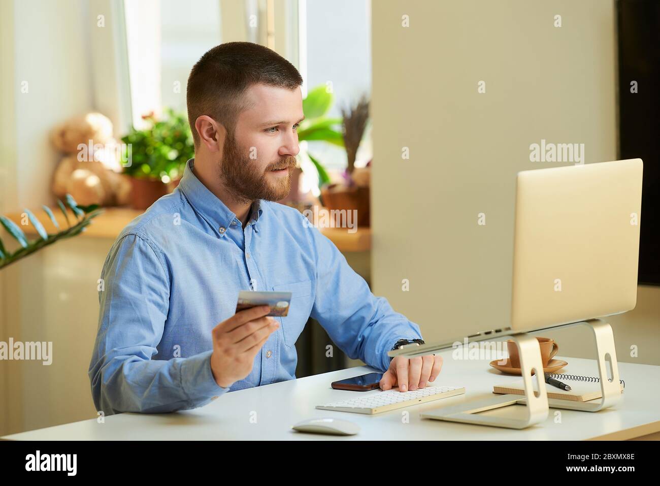A man searching for products to buy on an online store on his laptop ...