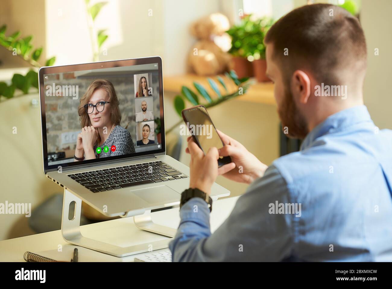 Back view of a male employee who is working remotely listening to his ...