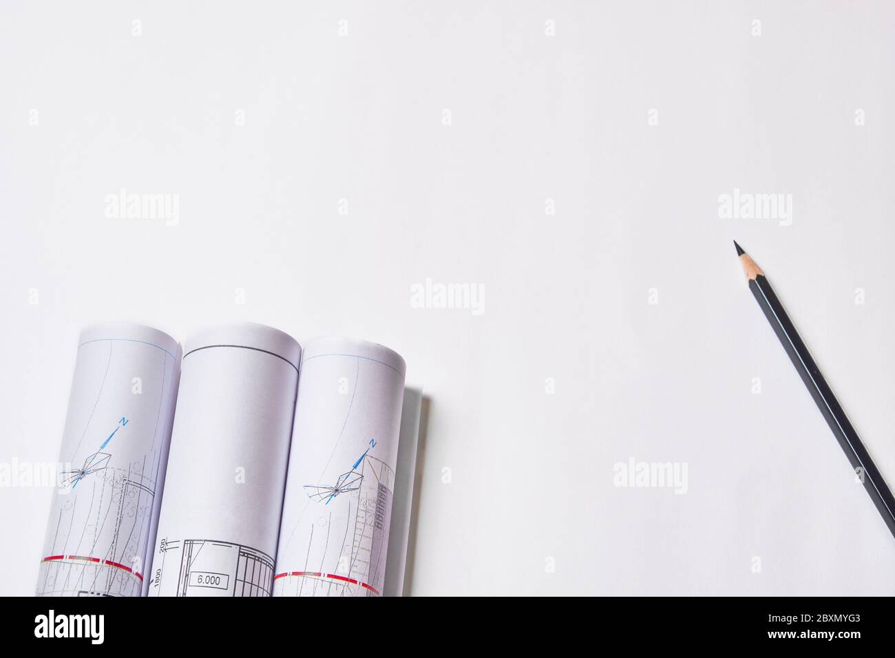 Rolled engineering drawings and pencil at blank white background with ...