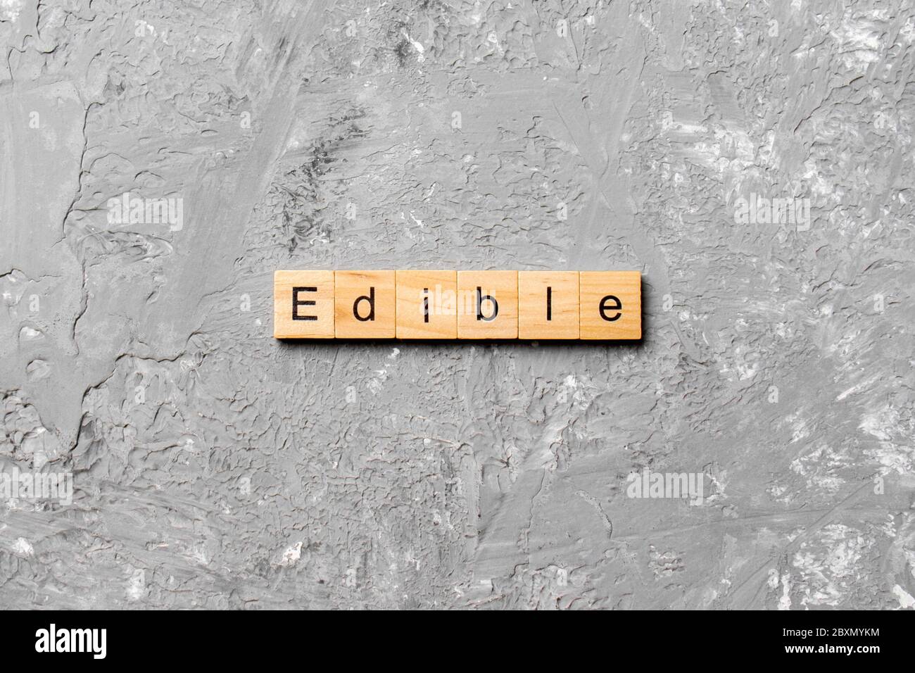 EDIBLE word written on wood block. EDIBLE text on cement table for your ...