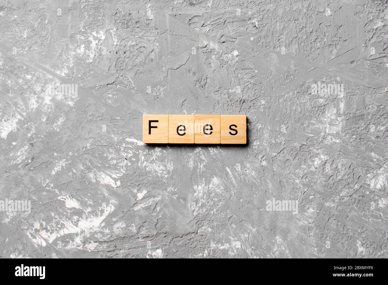 Fees word written on wood block. Fees text on cement table for your ...