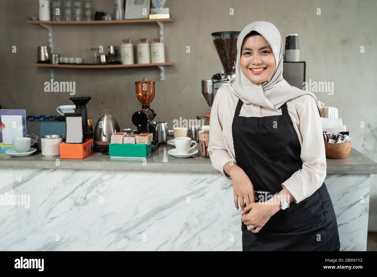 female veiled waitress with lean back arm standing at workplace in ...