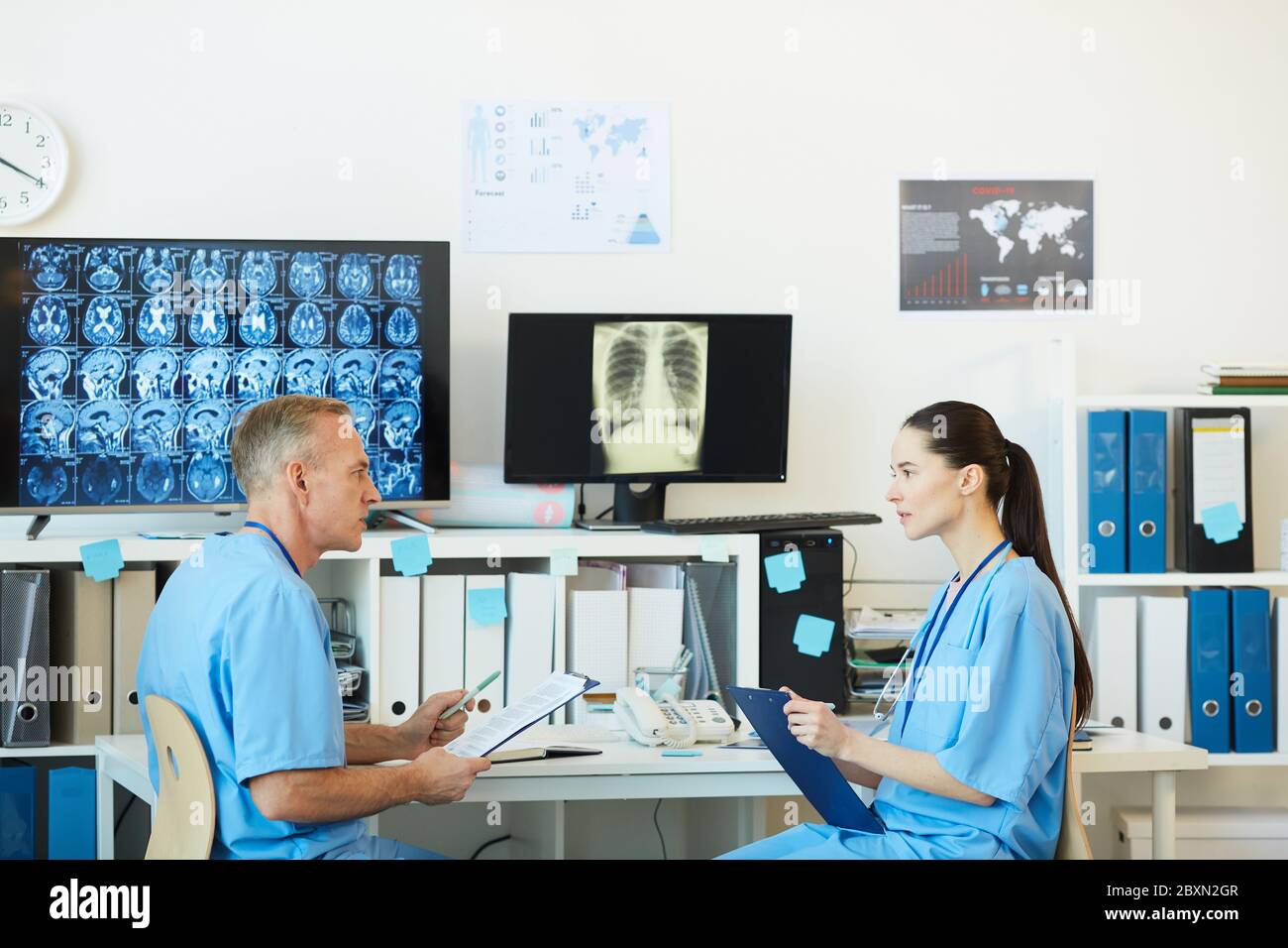 Side view portrait of two adult medics talking while sitting at ...