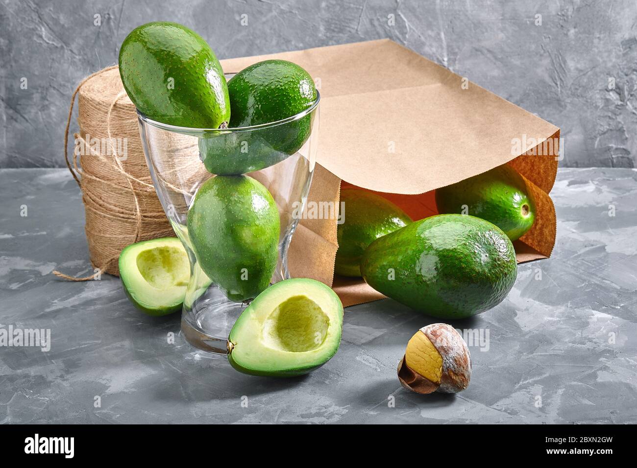 Avocado concept. Whole and cut avocados in a vase and lying on a gray ...