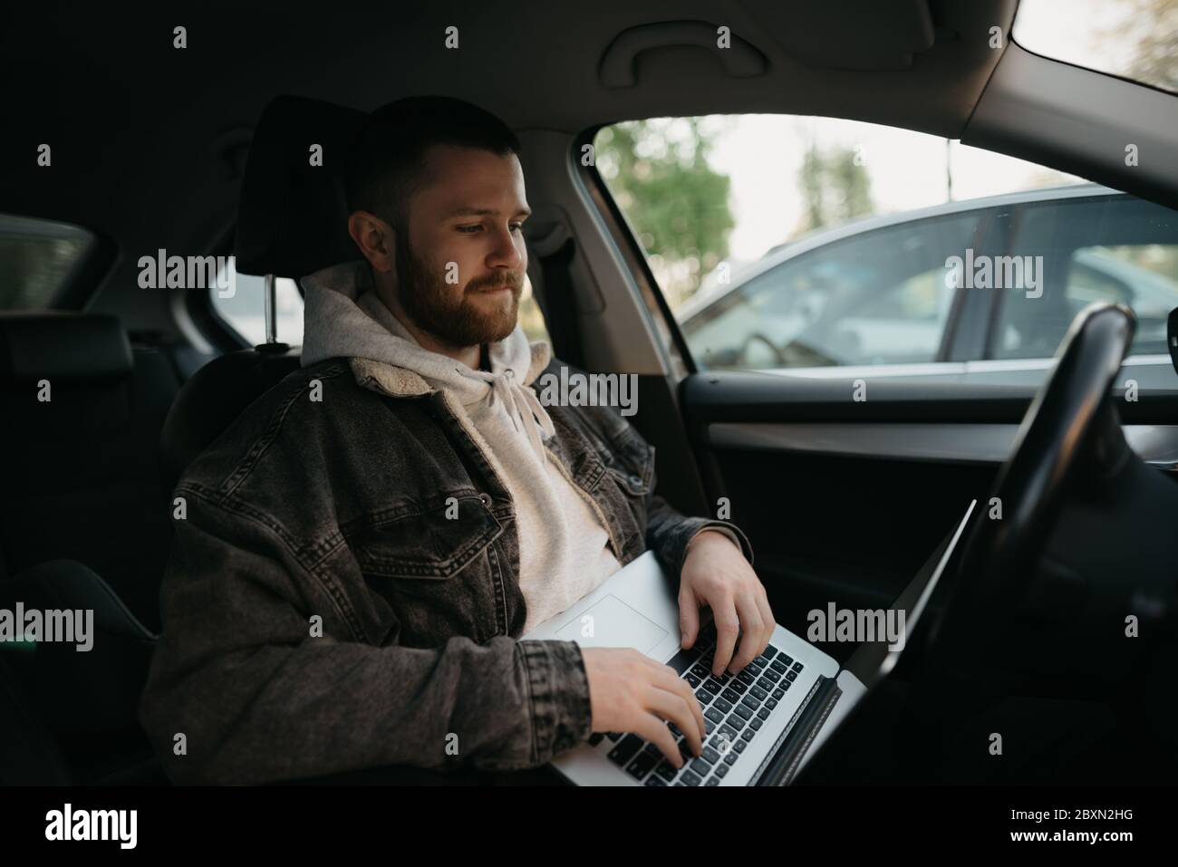 A happy man with a beard doing business online on his laptop computer ...