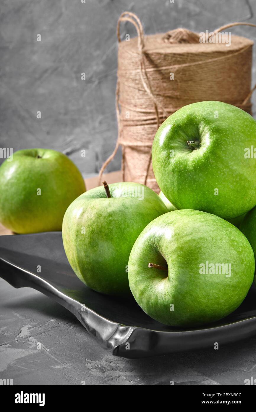 green apples lying on a gray background with a black plate ecological ...