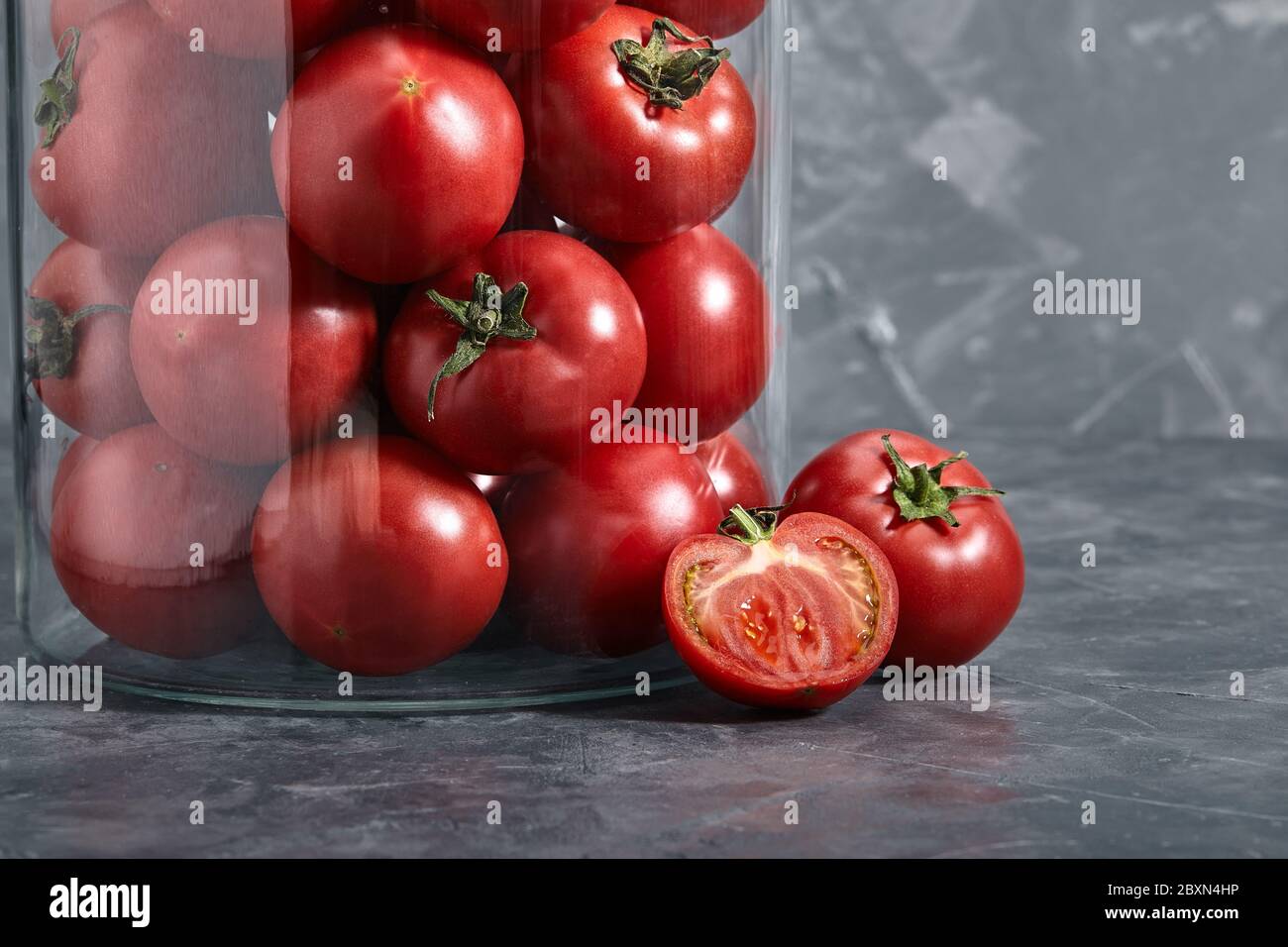 Red tomatoes in a glass vase on a gray background Close-up, tomato ...