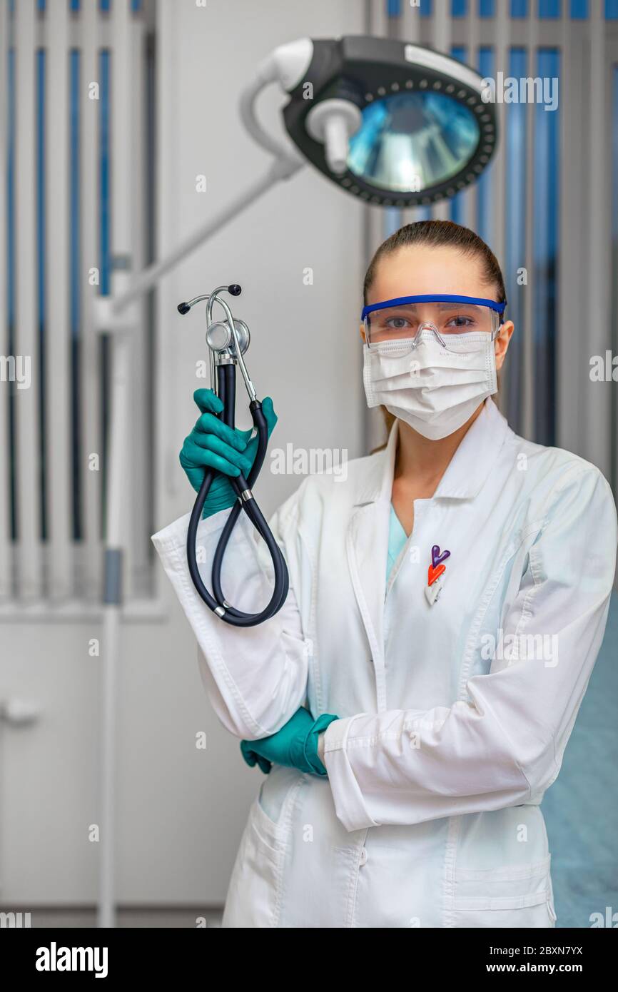 Doctor's hand in white coat holding a phonendoscope on the background ...