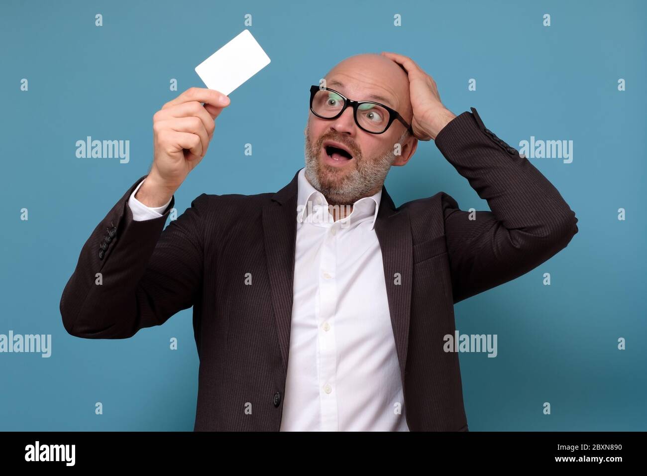 italian man holding credit card with hand on head, being shocked and ...