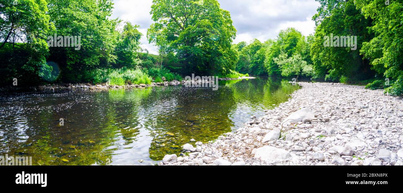 River Kent running over the rocks and pebbles with tree lined banks in ...