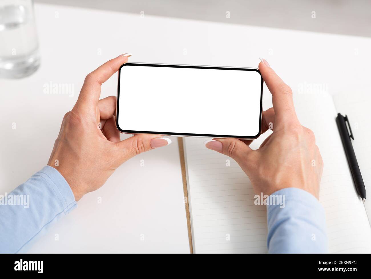 Using smartphone for work. Female hands hold phone on white desktop ...