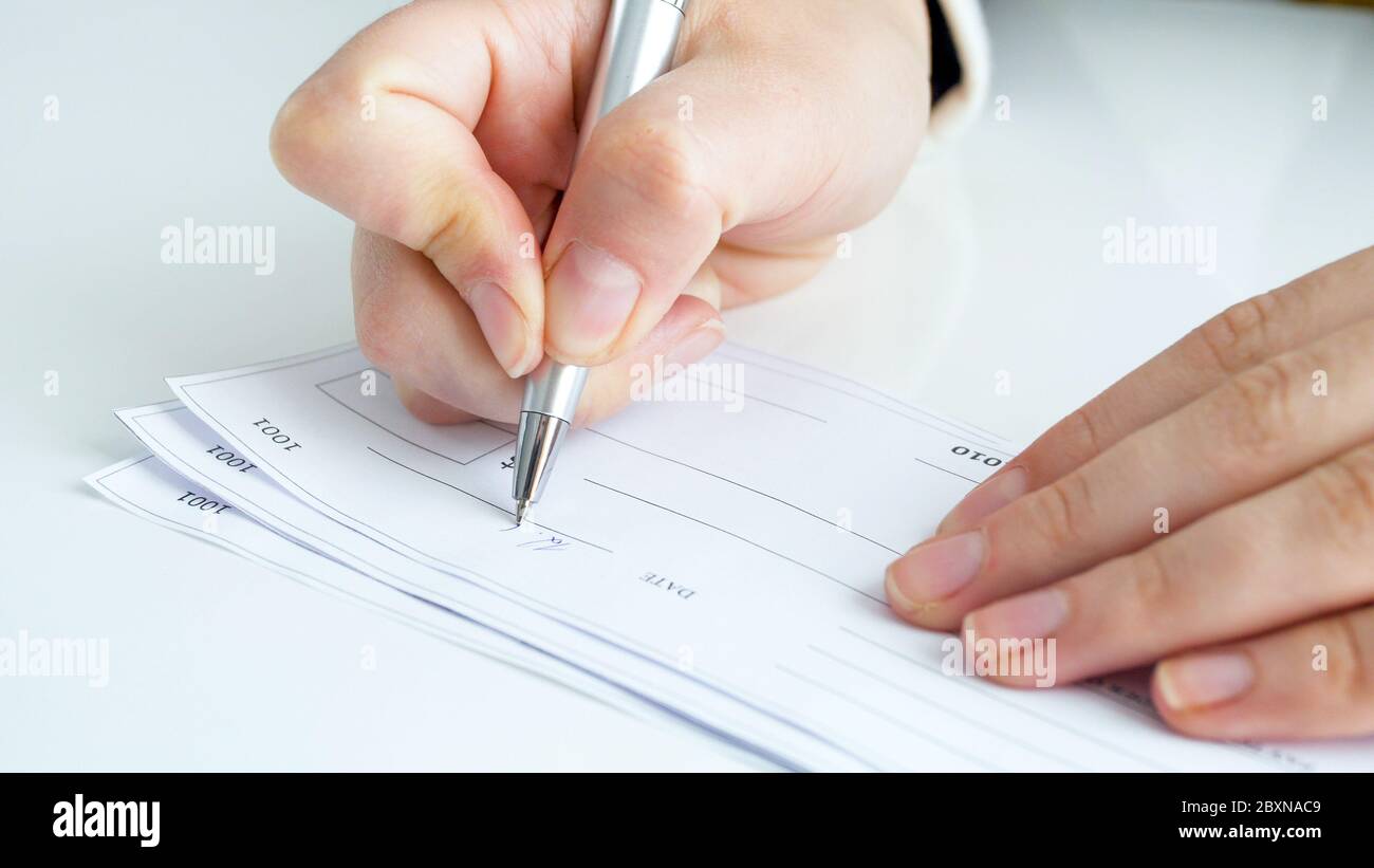 Closeup image of person signing banking cheque Stock Photo - Alamy
