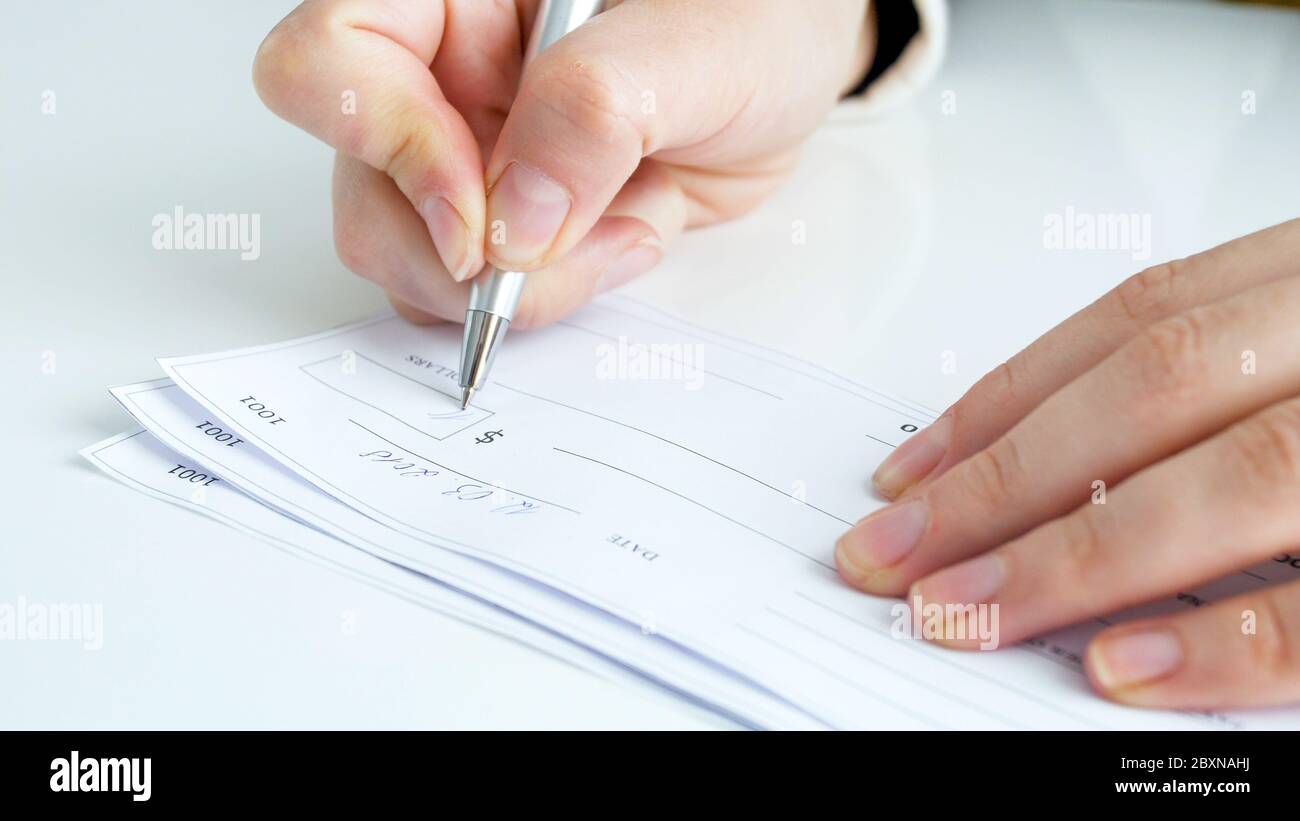 Businesswoman filling and signing banking cheque on office desk Stock ...
