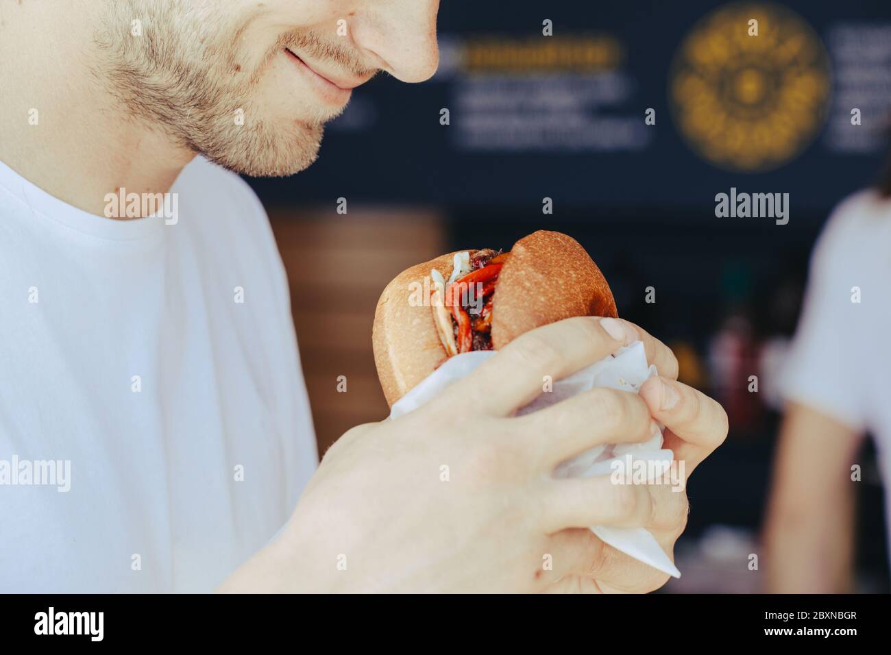 Close-up of man holds and bites hamburger, eating fast food, unhealthy ...